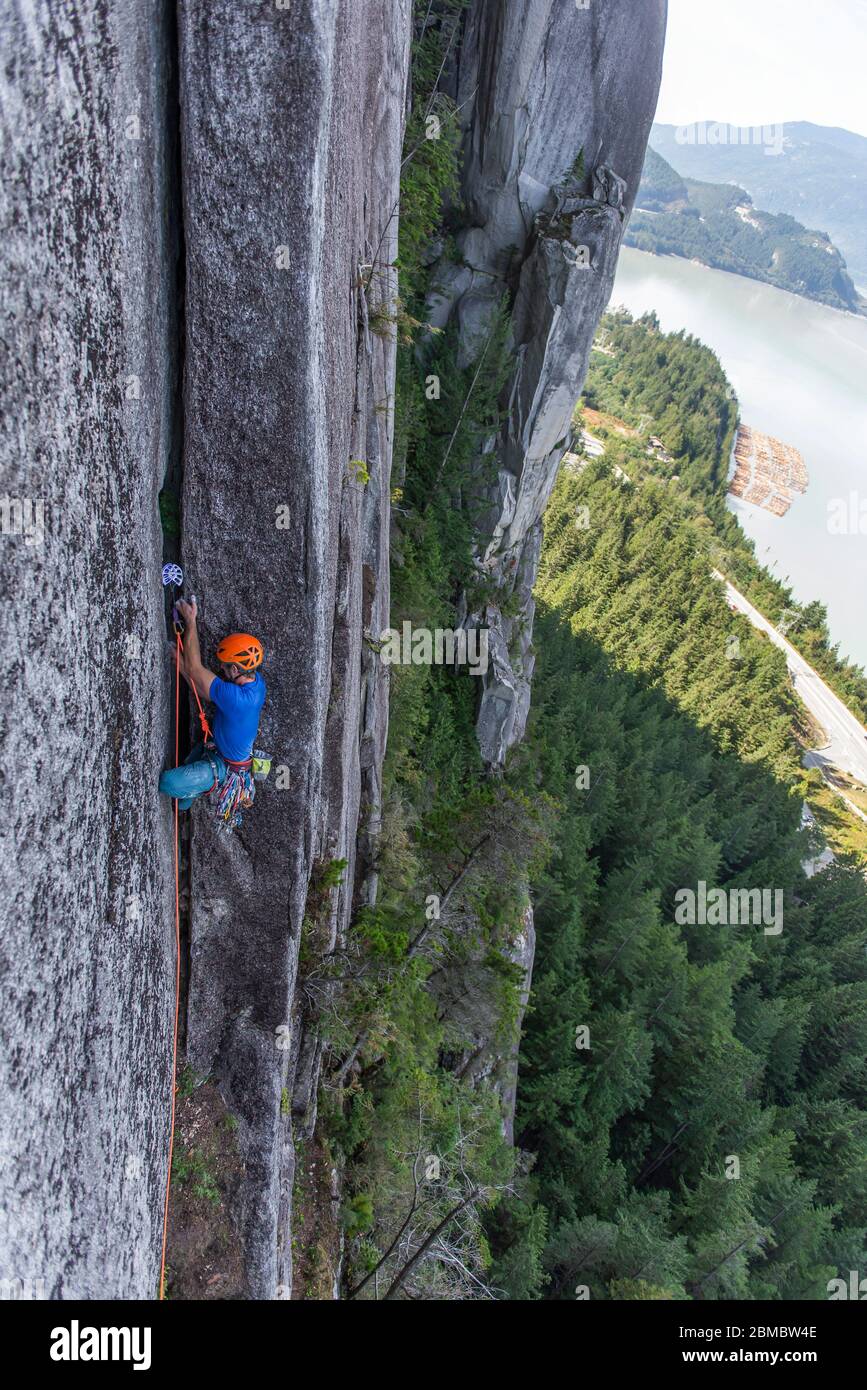 Side view of man climbing multi pitch route on pillar with ocean view ...