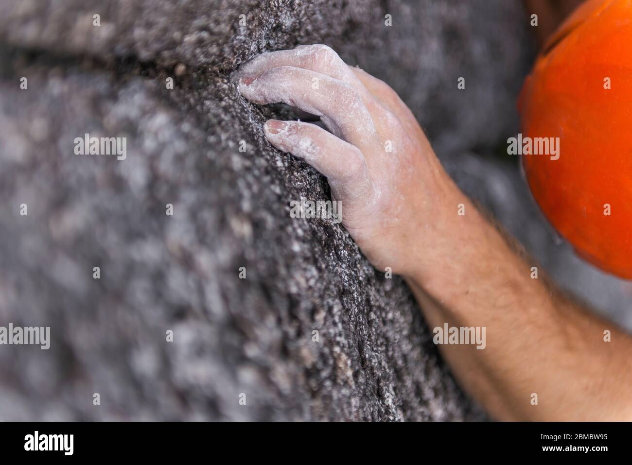 Close up of finger with chalk in tiny crack and helmet while climbing ...