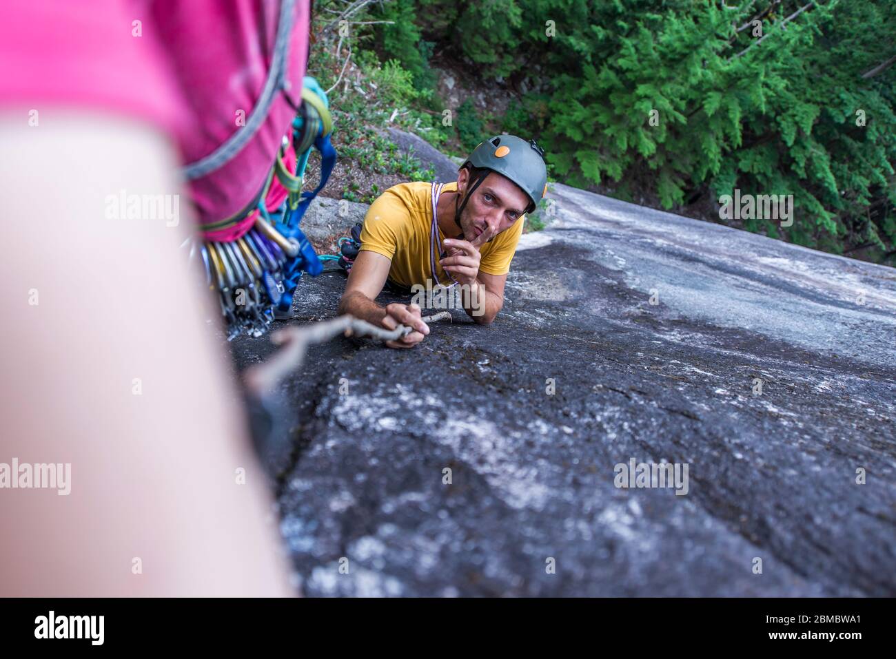 Man showing to shush and silence while poking climber with wood stick ...