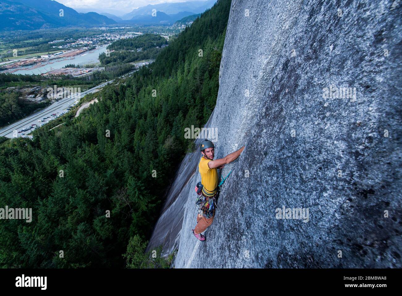 Man rock climbing on Squamish Chief looking at camera city background ...