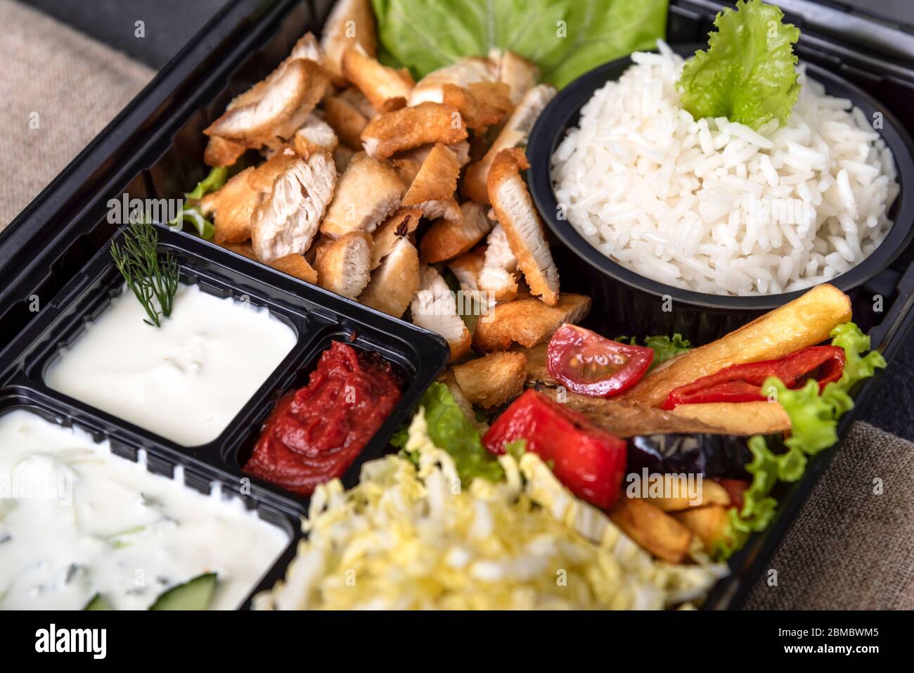 Traditional doner kebab in a black plastic container, sour cream, white ...