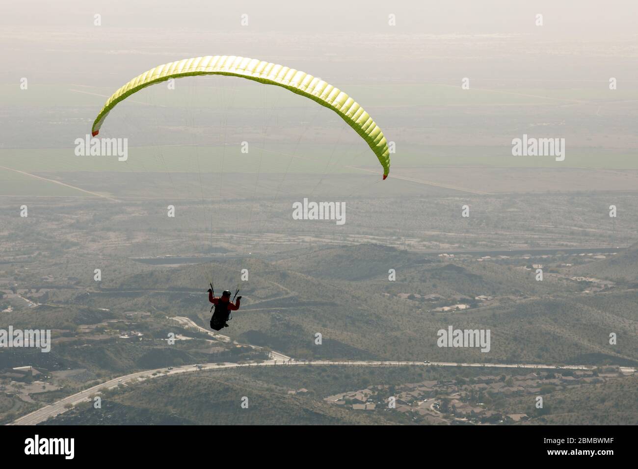 Man paragliding with parachute in the wind high above Phoenix suburbs ...