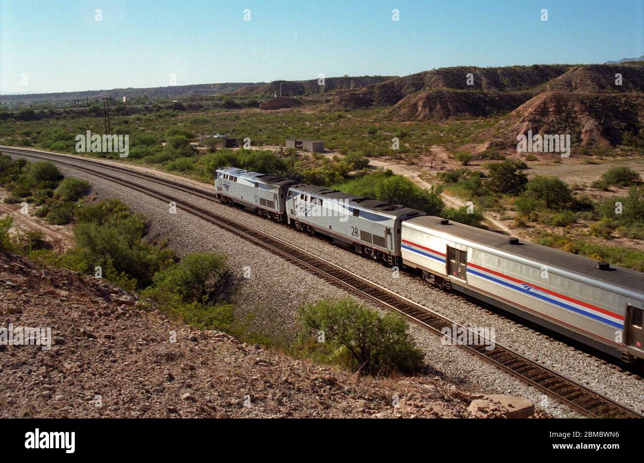Amtrak passenger train moves through frame from high vantage in desert ...