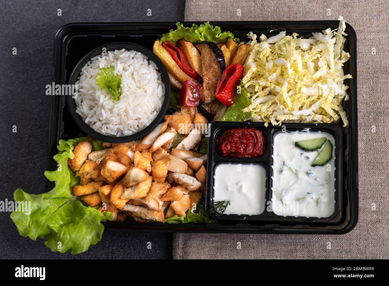 Traditional doner kebab in a black plastic container, sour cream, white ...