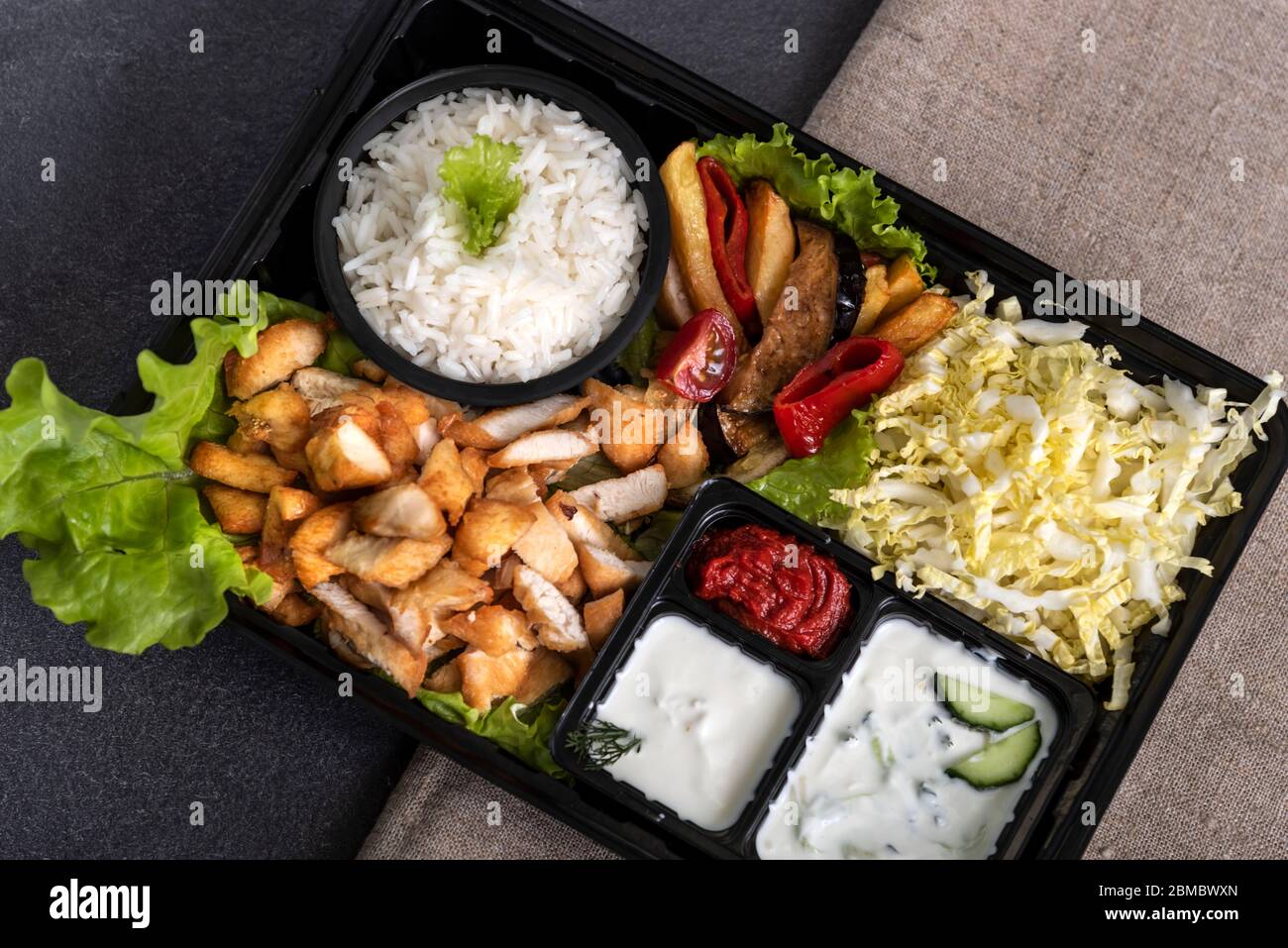 Traditional doner kebab in a black plastic container, sour cream, white ...