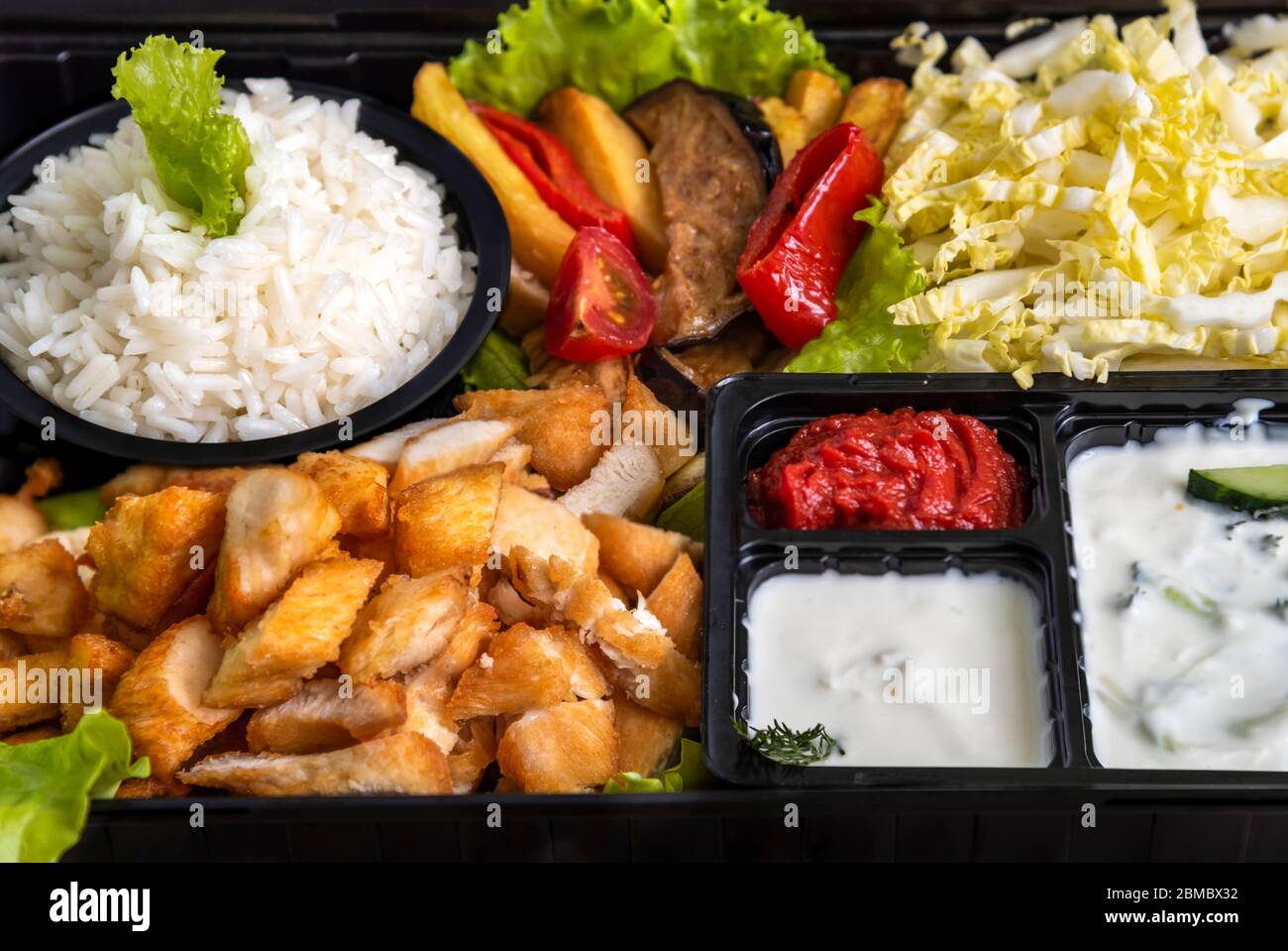 Traditional doner kebab in a black plastic container, sour cream, white ...