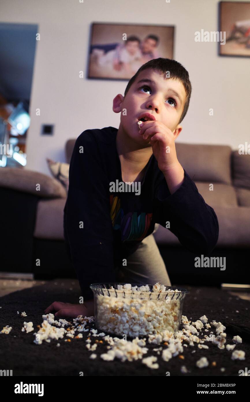 a kid eats popcorn at home while watching a movie Stock Photo - Alamy