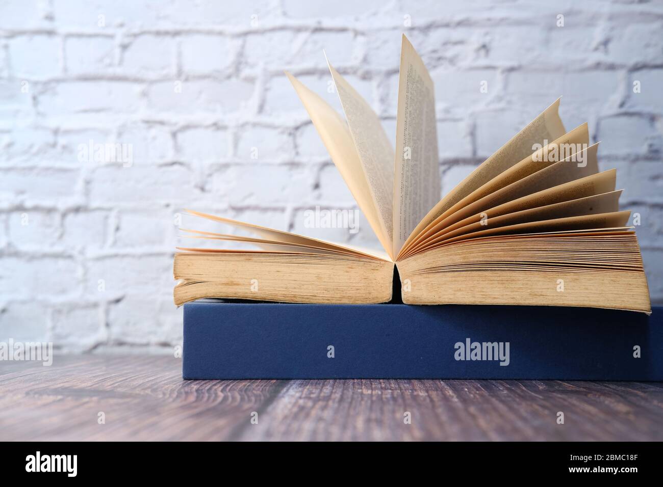 open book on table against a wall Stock Photo - Alamy