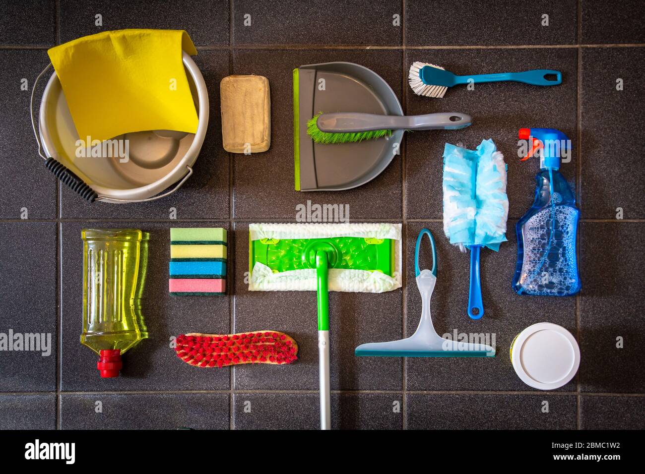 Flat lay with collection of cleaning materials on a black tile ...
