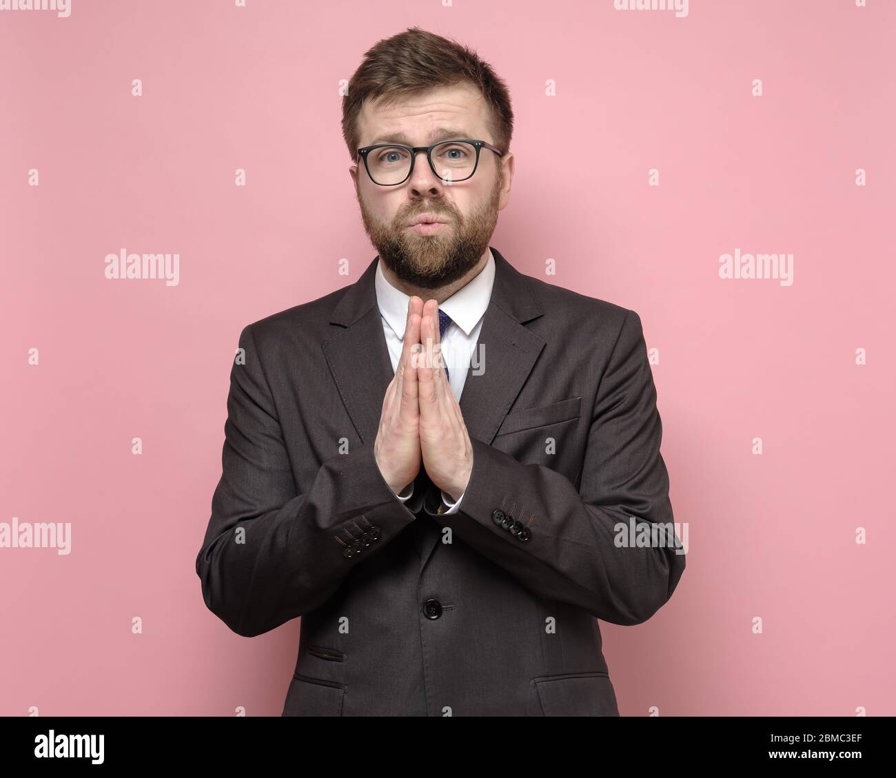 Attractive man in suit with an imploring expression on face folded ...