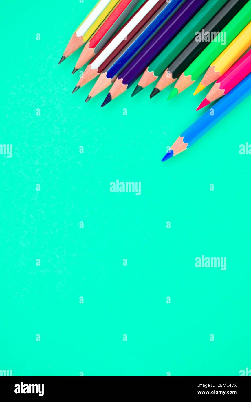 Some different color wood pencil crayons placed on top of a light blue ...