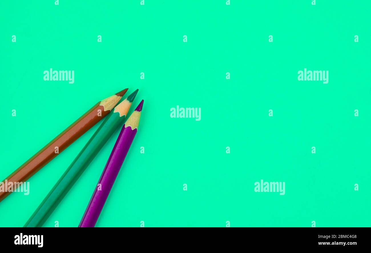 Three different color wood pencil crayons placed on top of a light blue ...