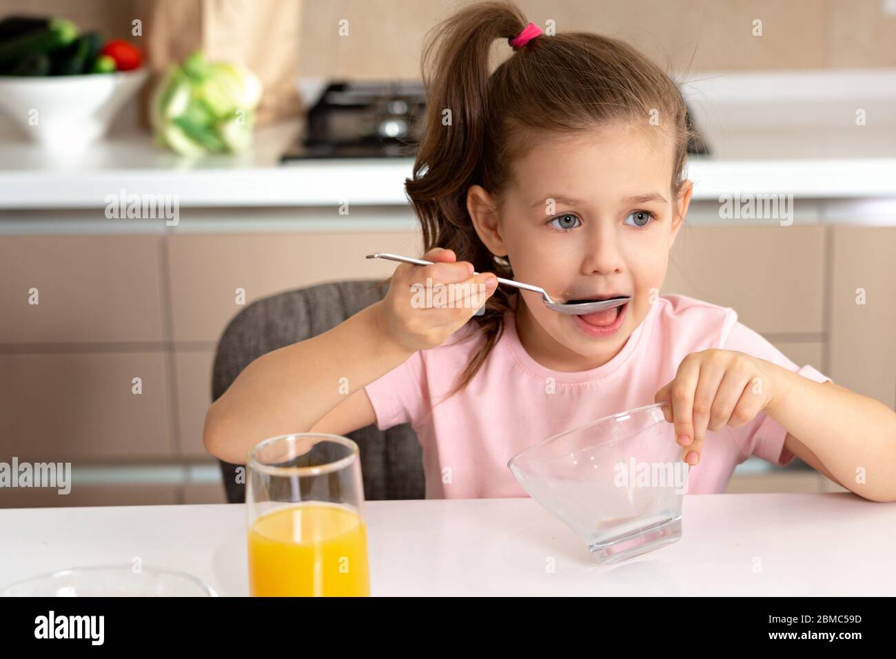 Pretty girl eating breakfast in the kitchen alone Stock Photo - Alamy