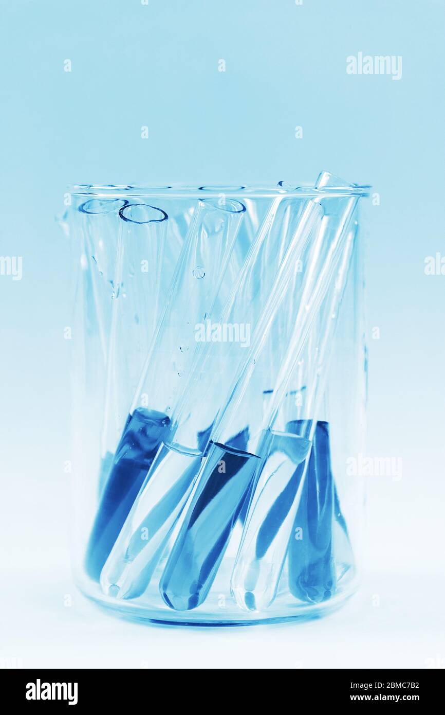 Test tubes with different samples of the solutions in the glass beaker ...