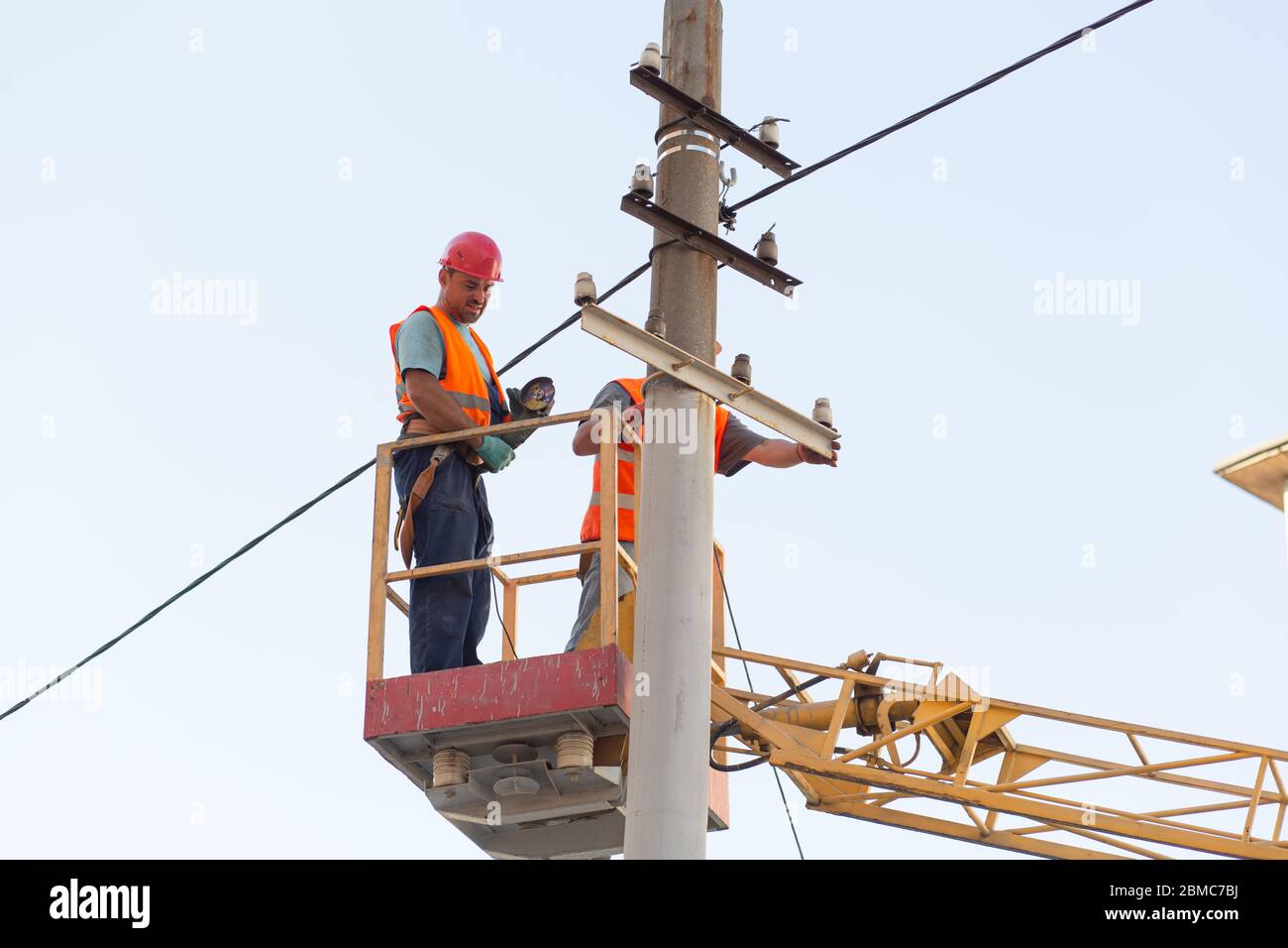 electricians on the pillars install the mount for the power line ...