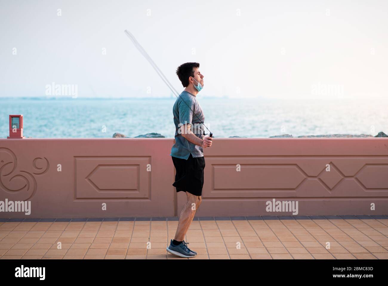 Man exercising with a jumping rope and wearing protective surgical mask ...