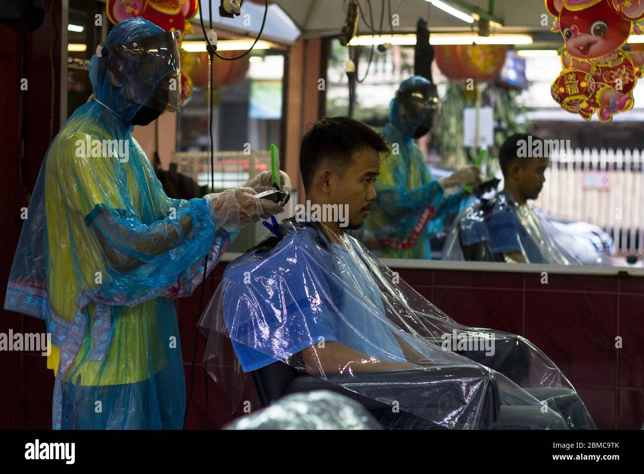 Jakarta, Indonesia. 8th May, 2020. A barber cuts the hair of its ...