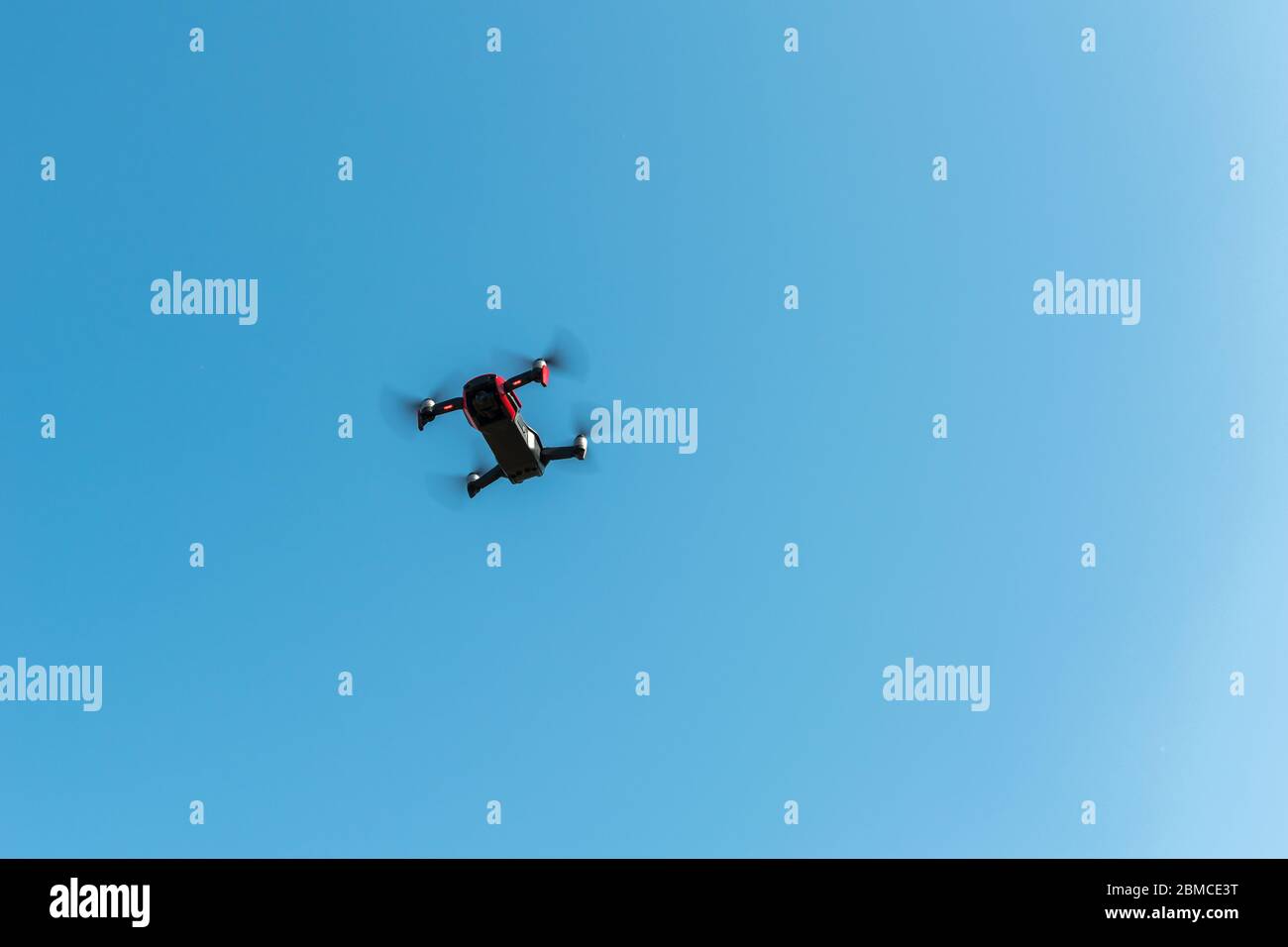 Small sized red drone with high resolution camera hovering in air for ...