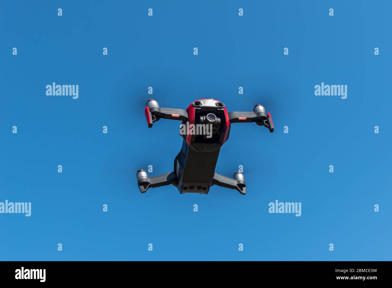 Small sized red drone with high resolution camera hovering in air for ...