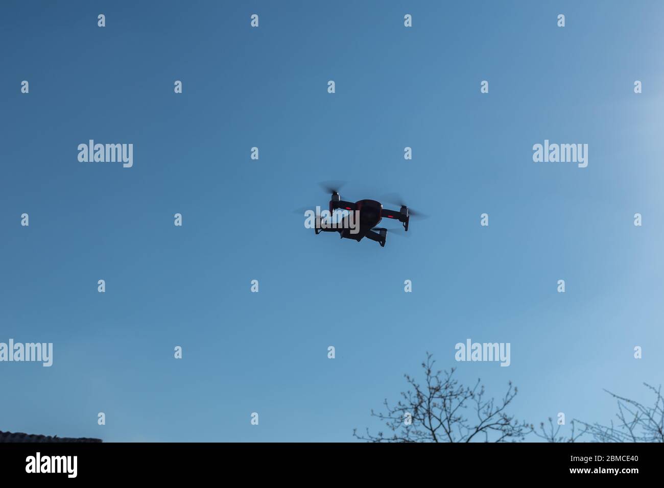 Small sized red drone with high resolution camera hovering in air for ...