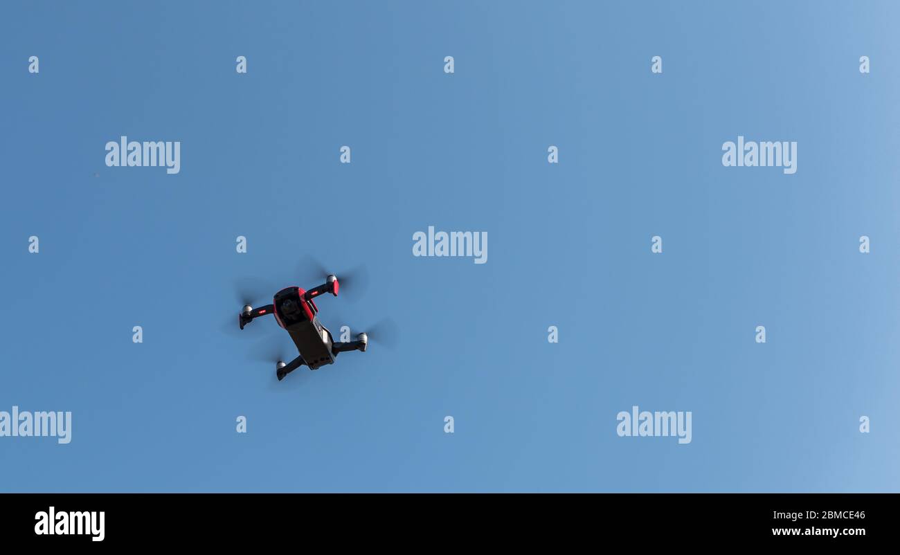 Small sized red drone with high resolution camera hovering in air for ...