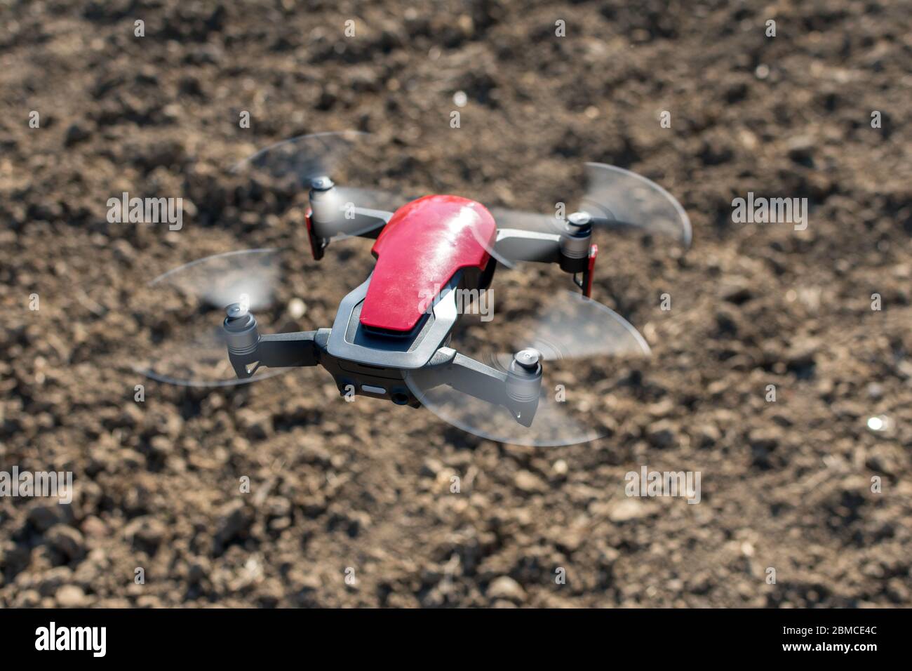 Small sized red drone with high resolution camera hovering in air for ...