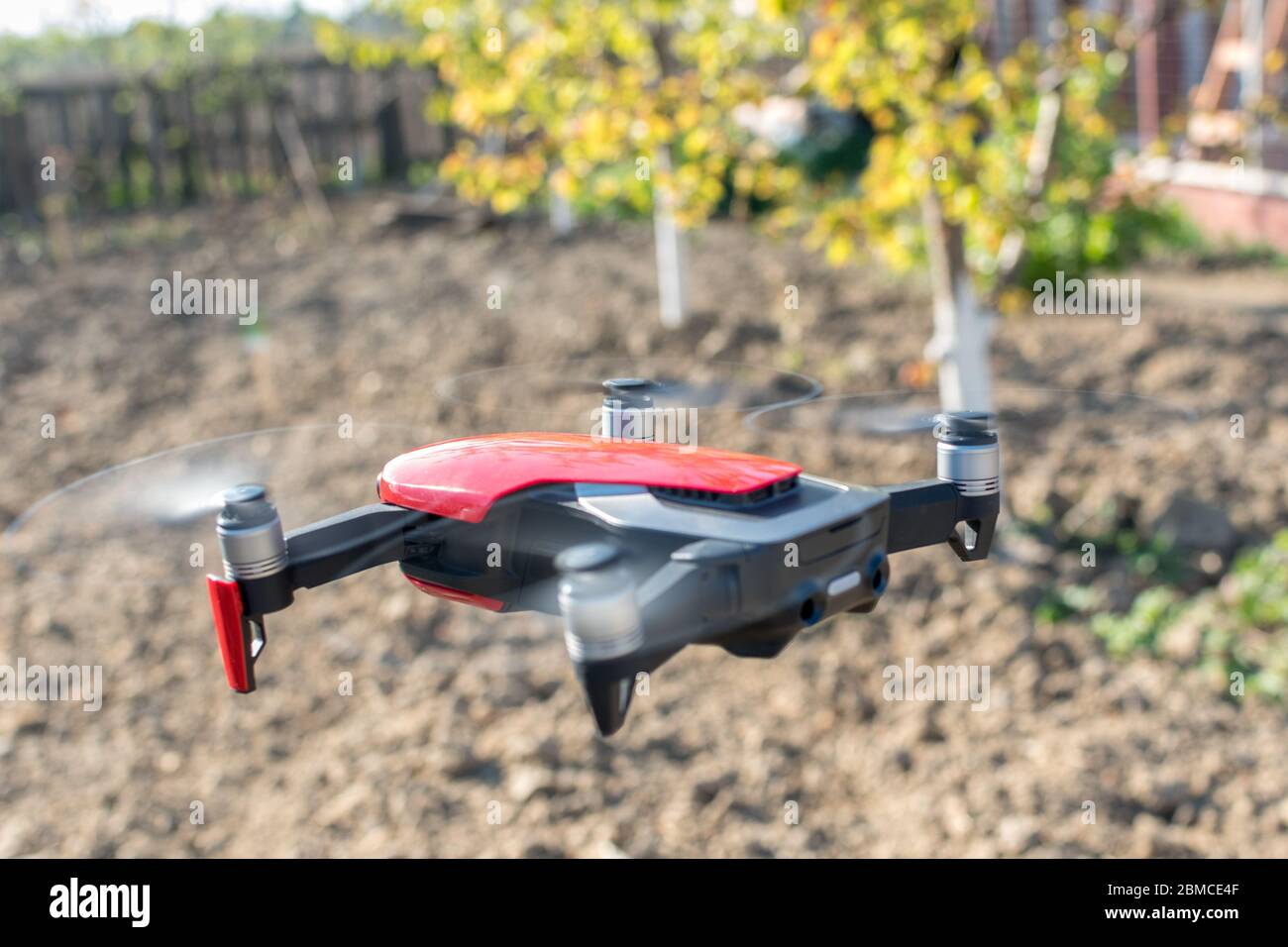 Small sized red drone with high resolution camera hovering in air for ...