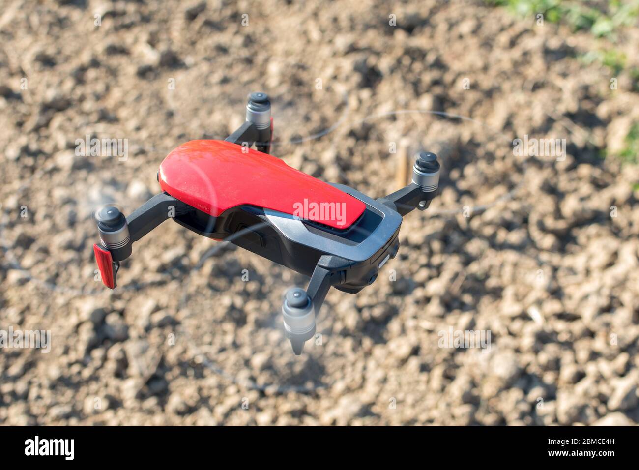 Small sized red drone with high resolution camera hovering in air for ...