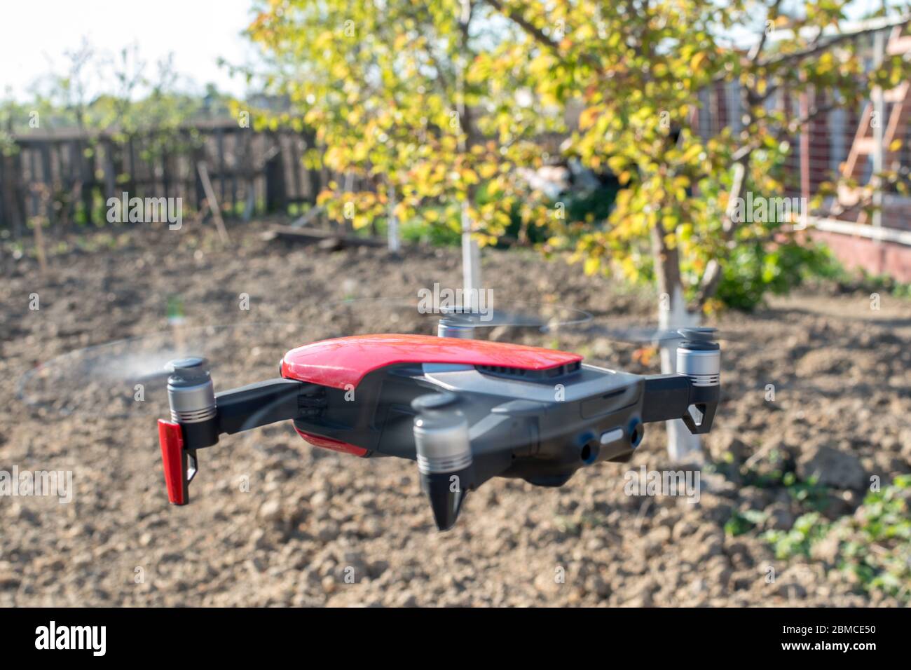 Small sized red drone with high resolution camera hovering in air for ...