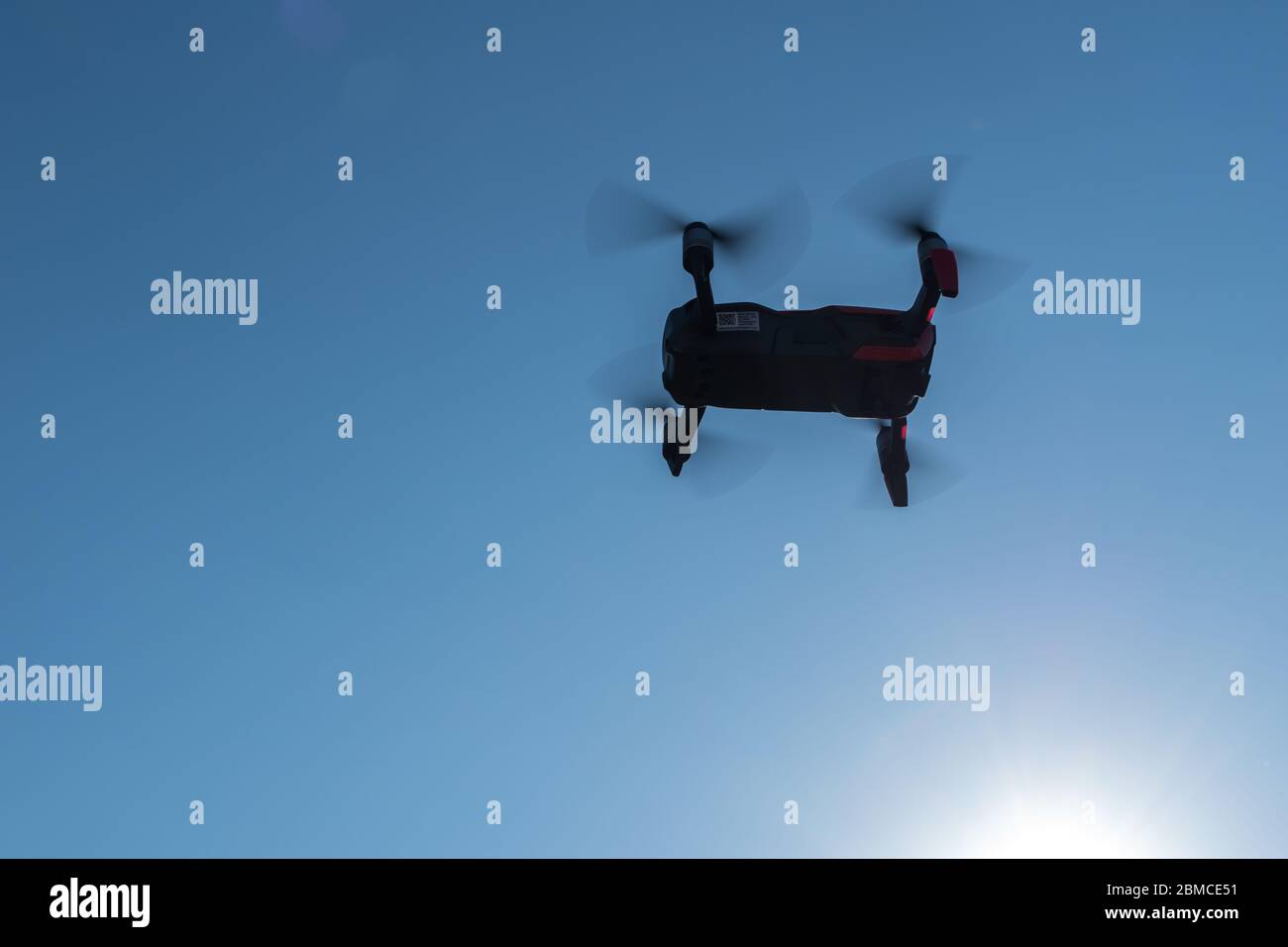 Small sized red drone with high resolution camera hovering in air for ...