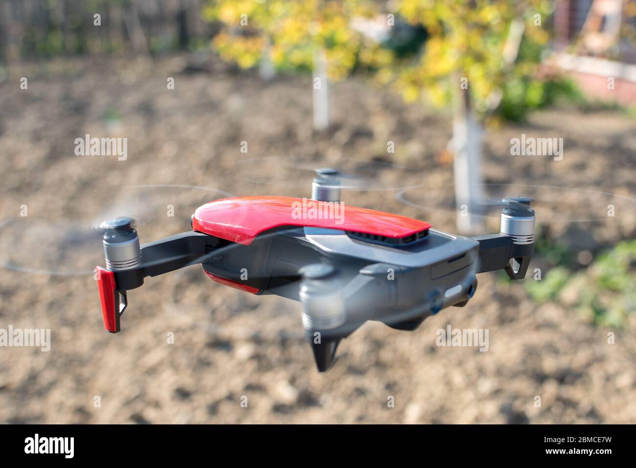 Small sized red drone with high resolution camera hovering in air for ...