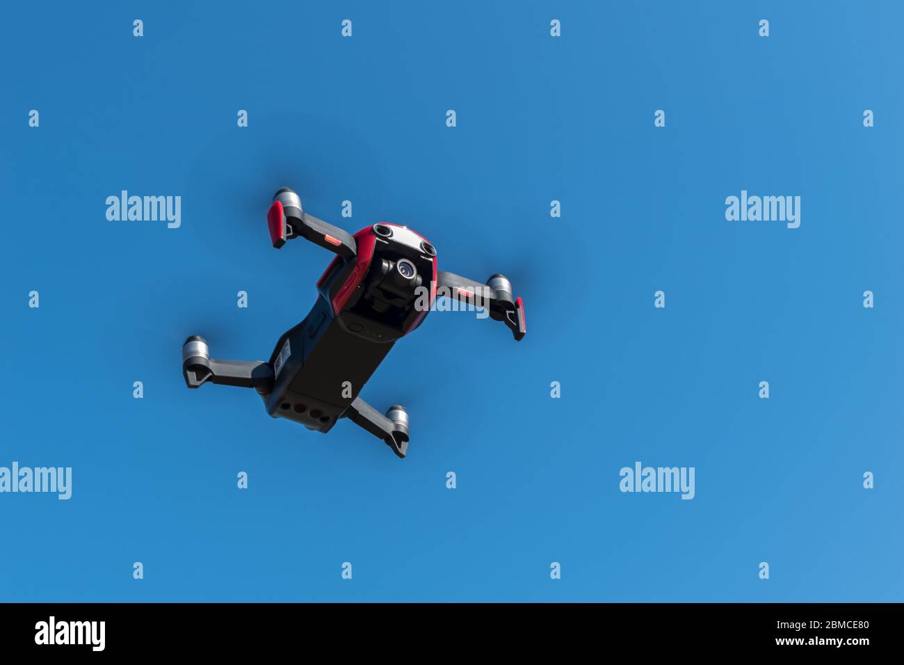 Small sized red drone with high resolution camera hovering in air for ...