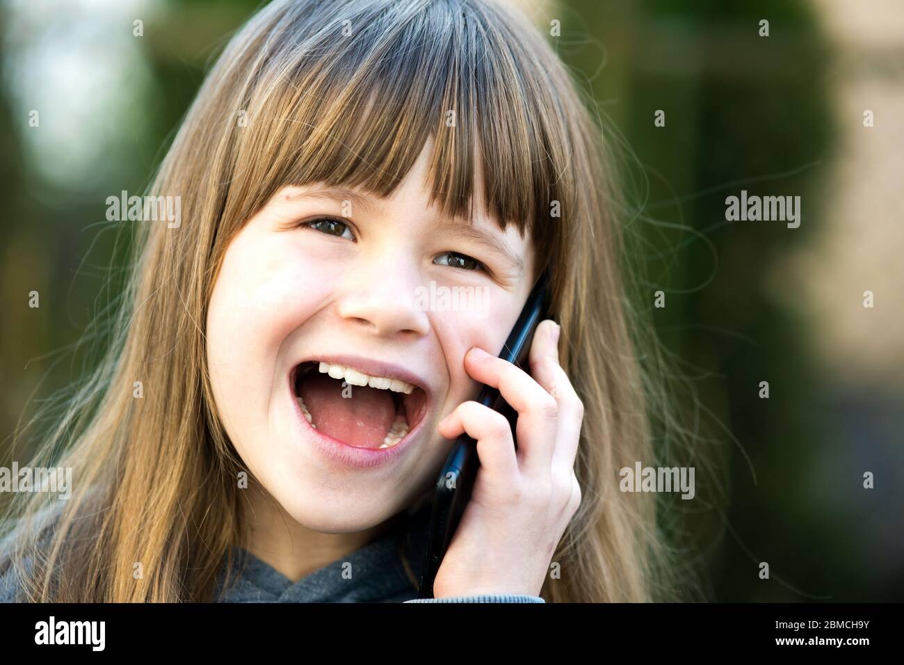 Portrait of pretty child girl with long hair talking on cell phone ...