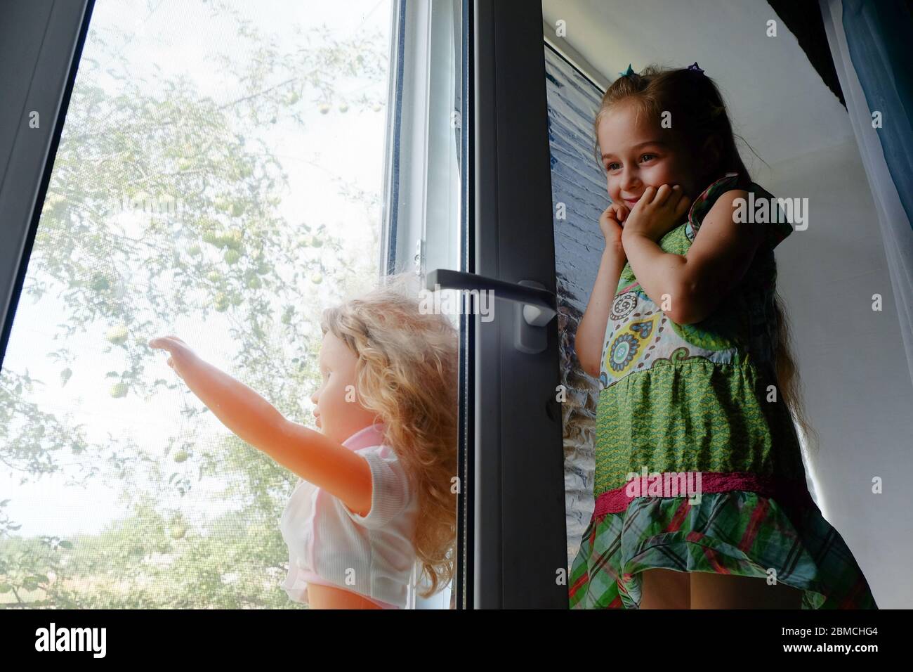 Little girl by the window. A 5 year old girl sits by the window at home ...