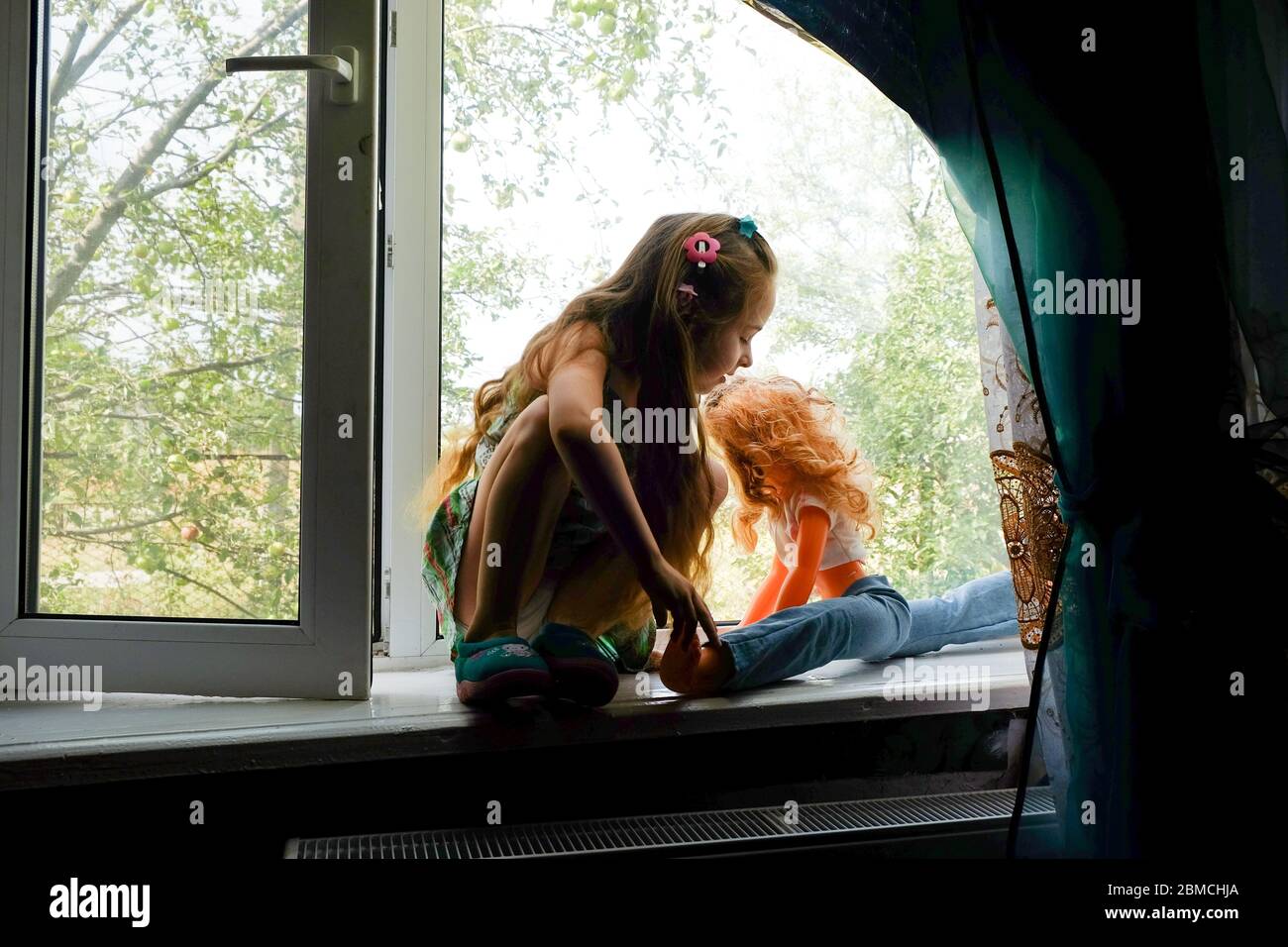 Little girl by the window. A 5 year old girl sits by the window at home ...