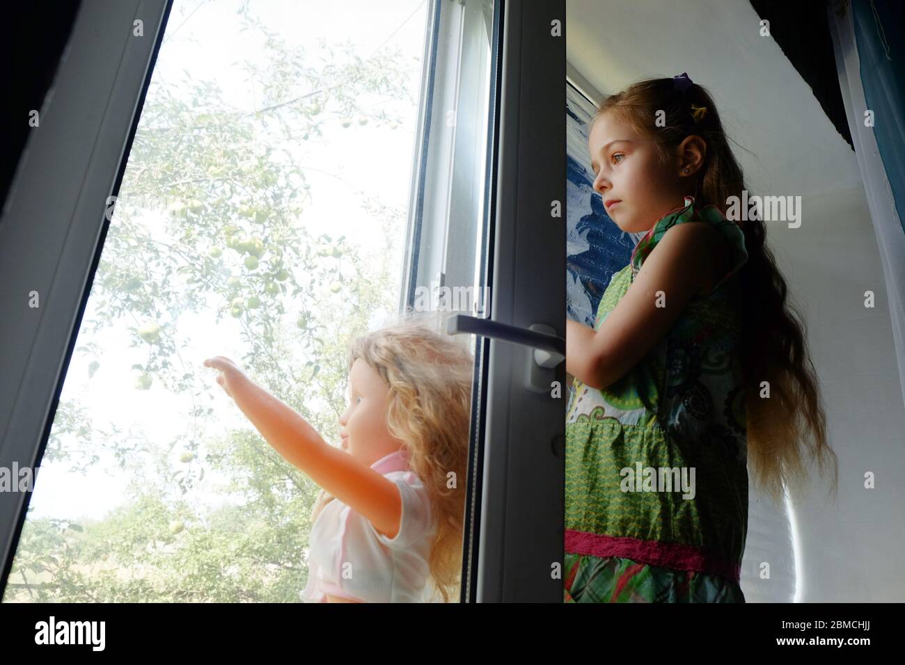 Little girl by the window. A 5 year old girl sits by the window at home ...
