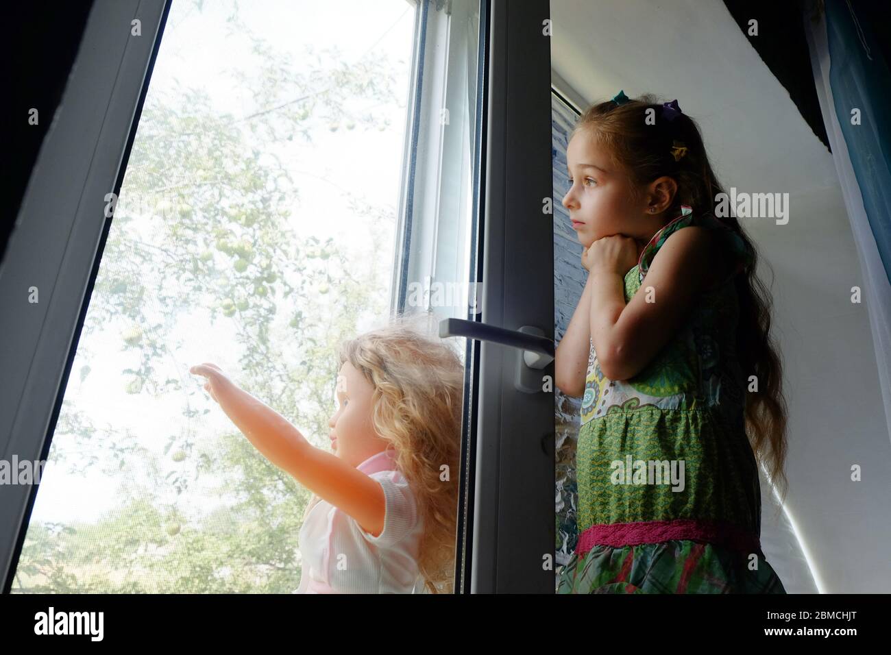Little girl by the window. A 5 year old girl sits by the window at home ...