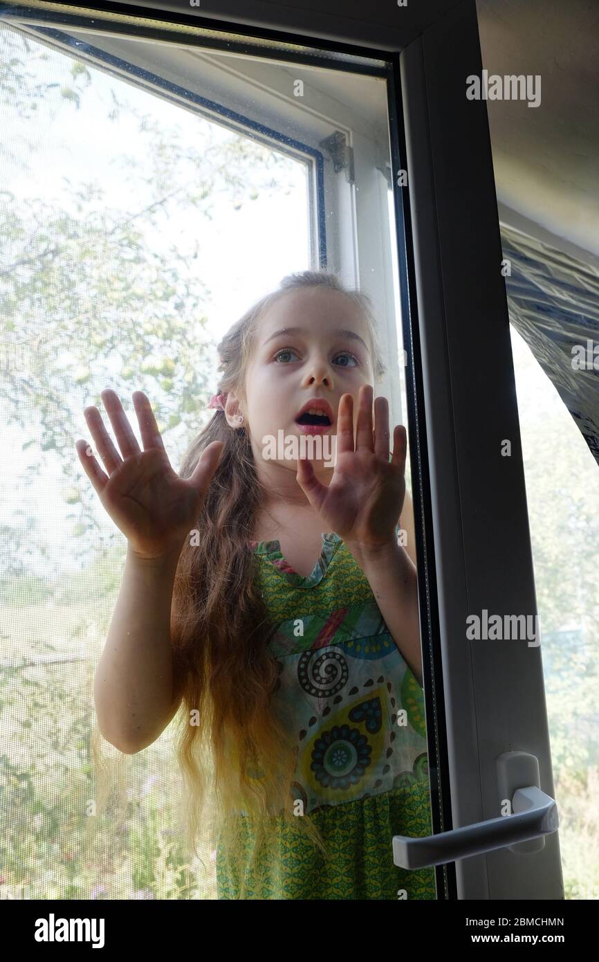 Little girl by the window. A 5 year old girl sits by the window at home ...