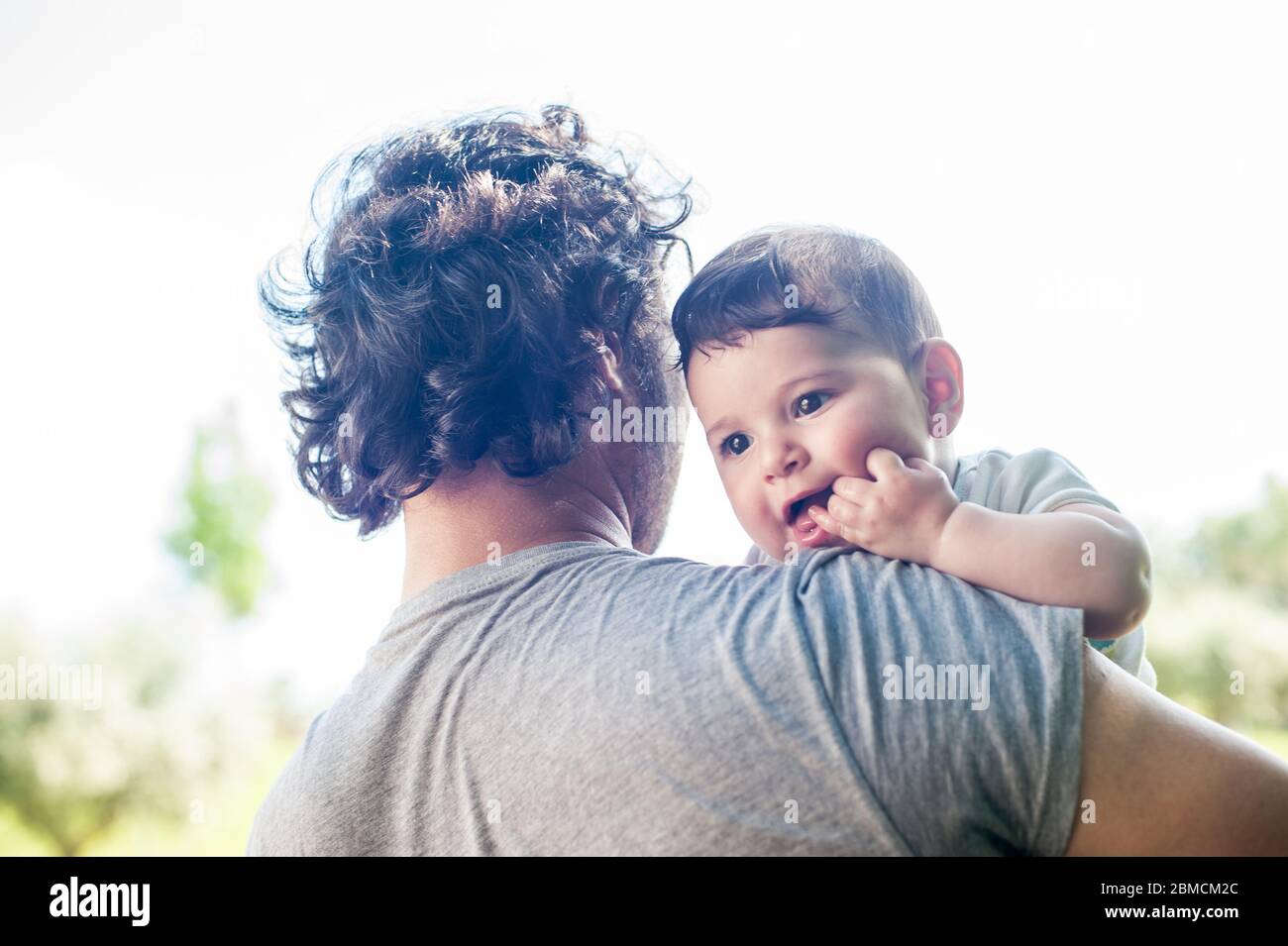father with his back to the camera holding his baby boy in his arms at ...