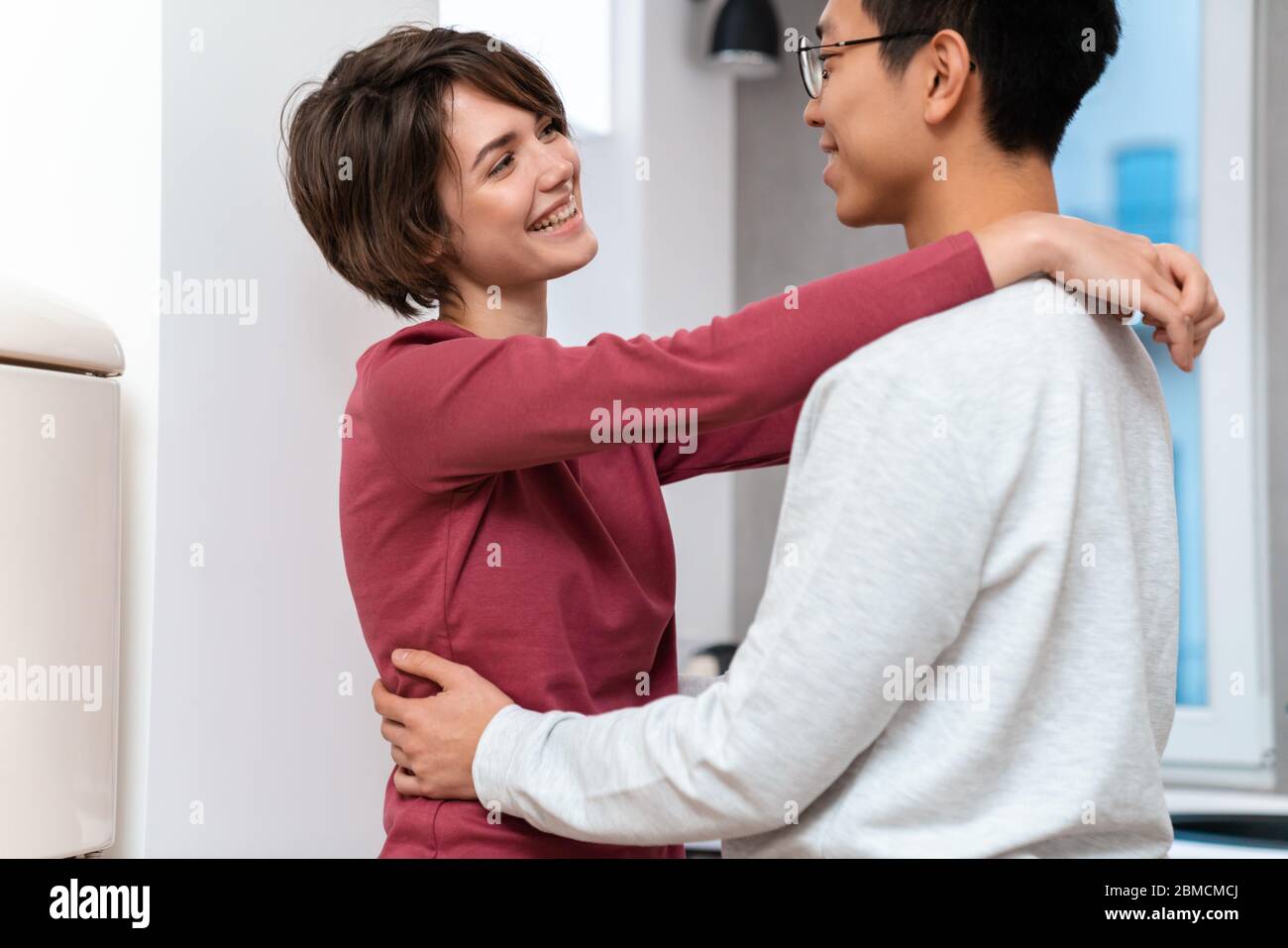 Photo of romantic multinational couple laughing and hugging while ...
