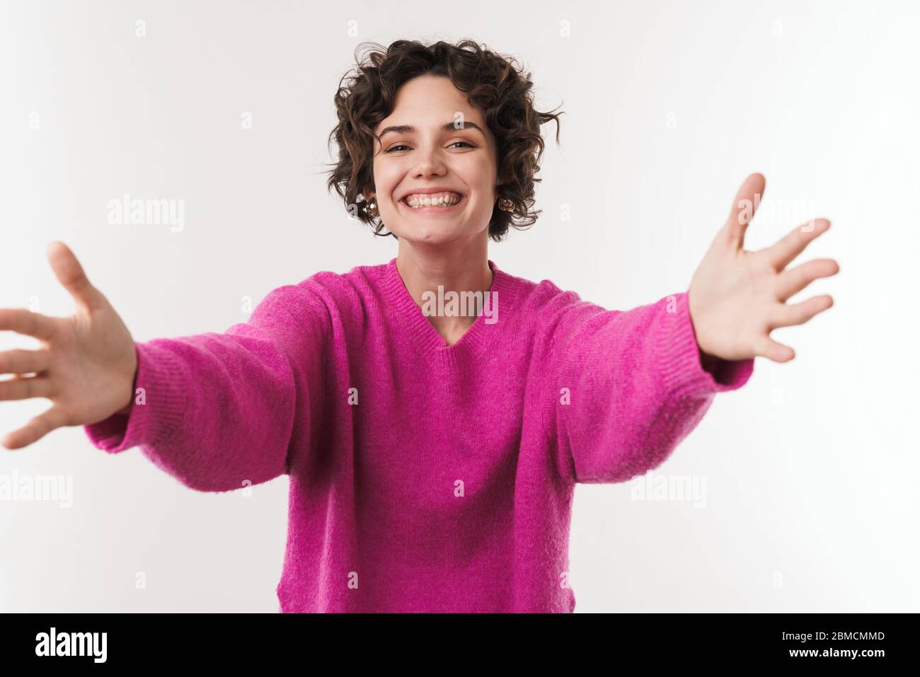 Image of pleased curly woman reaching her arms forward and smiling ...
