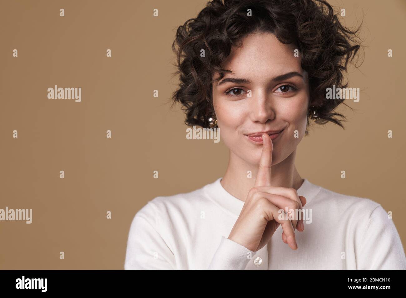 Image of pleased young woman smiling and gesturing quiet sign isolated ...