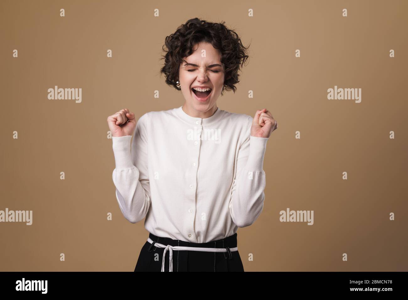 Image of excited beautiful woman screaming and making winner gesture ...