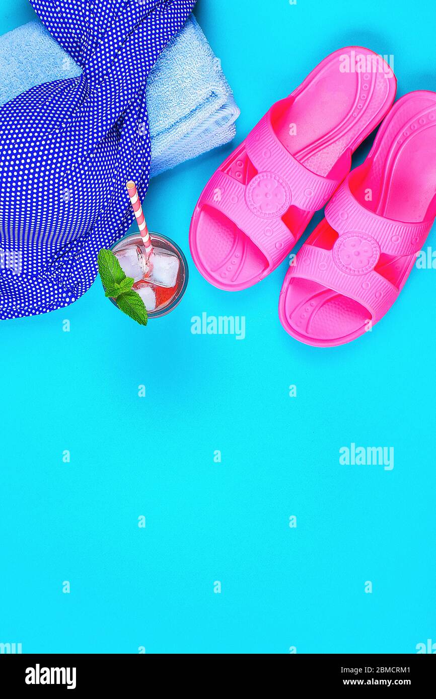 Flip-flops, swimsuit, towel and ice cocktail on a blue pastel ...