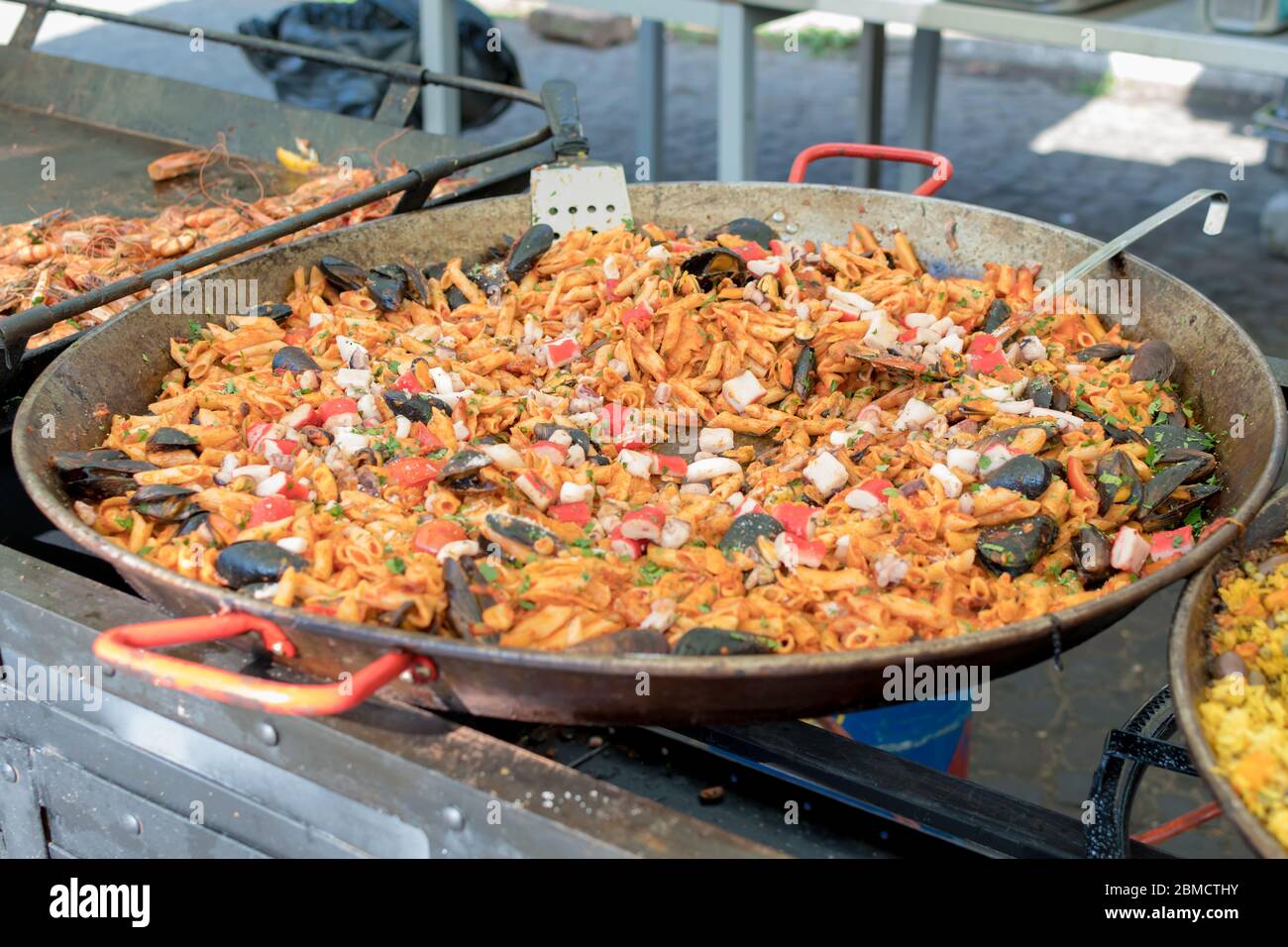 Fresh seafood penne tomato pasta cooking in large wok pan during hotel ...
