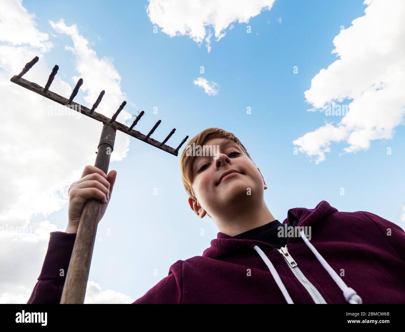 Caucasian boy posing with rake Stock Photo - Alamy