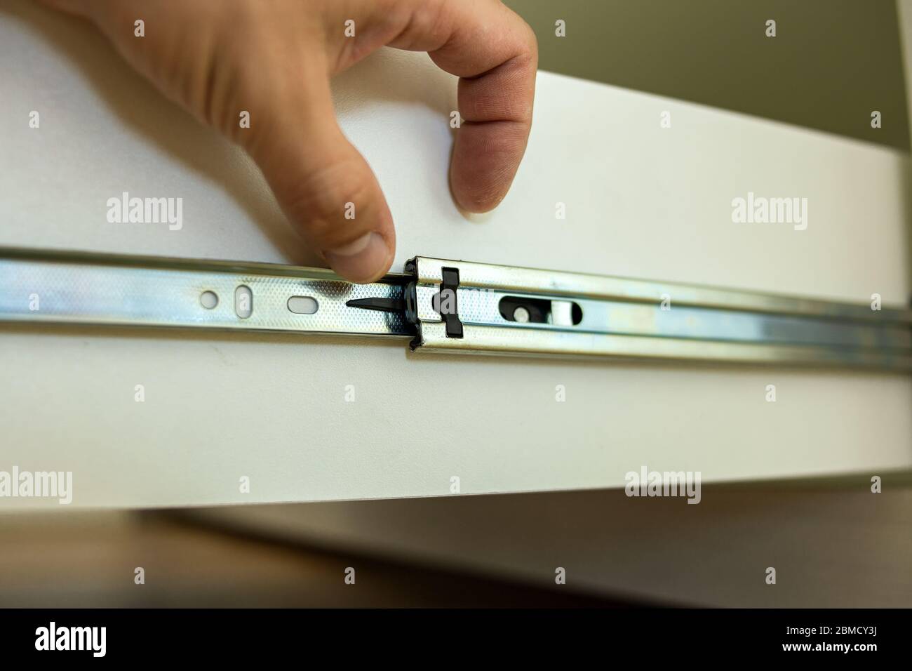 Close up of carpenter hands installing wooden drawer on sliding skids ...