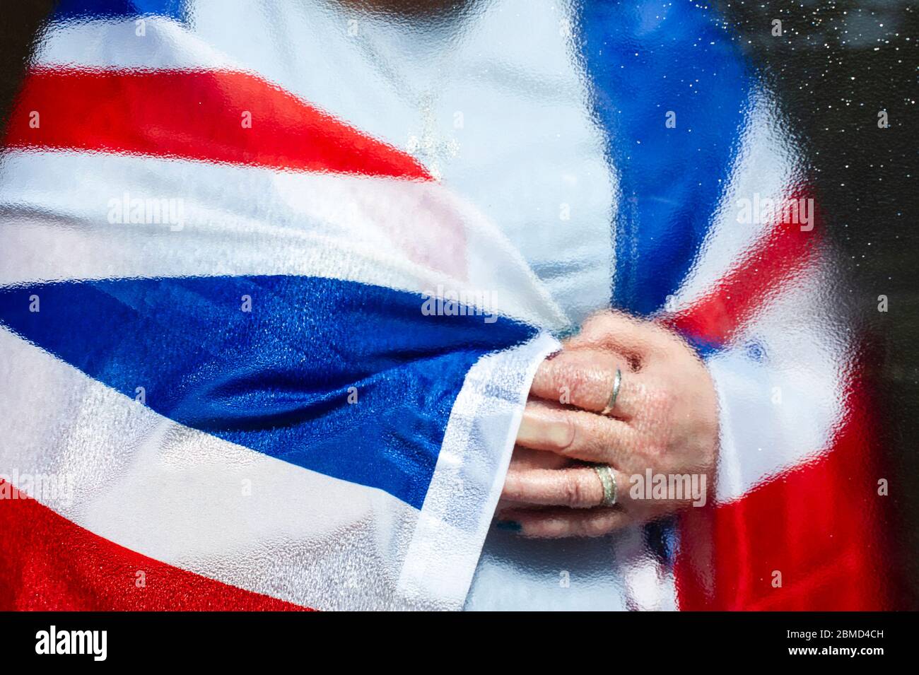 Woman draping Union Jack flag over her shoulders behind glass on St ...