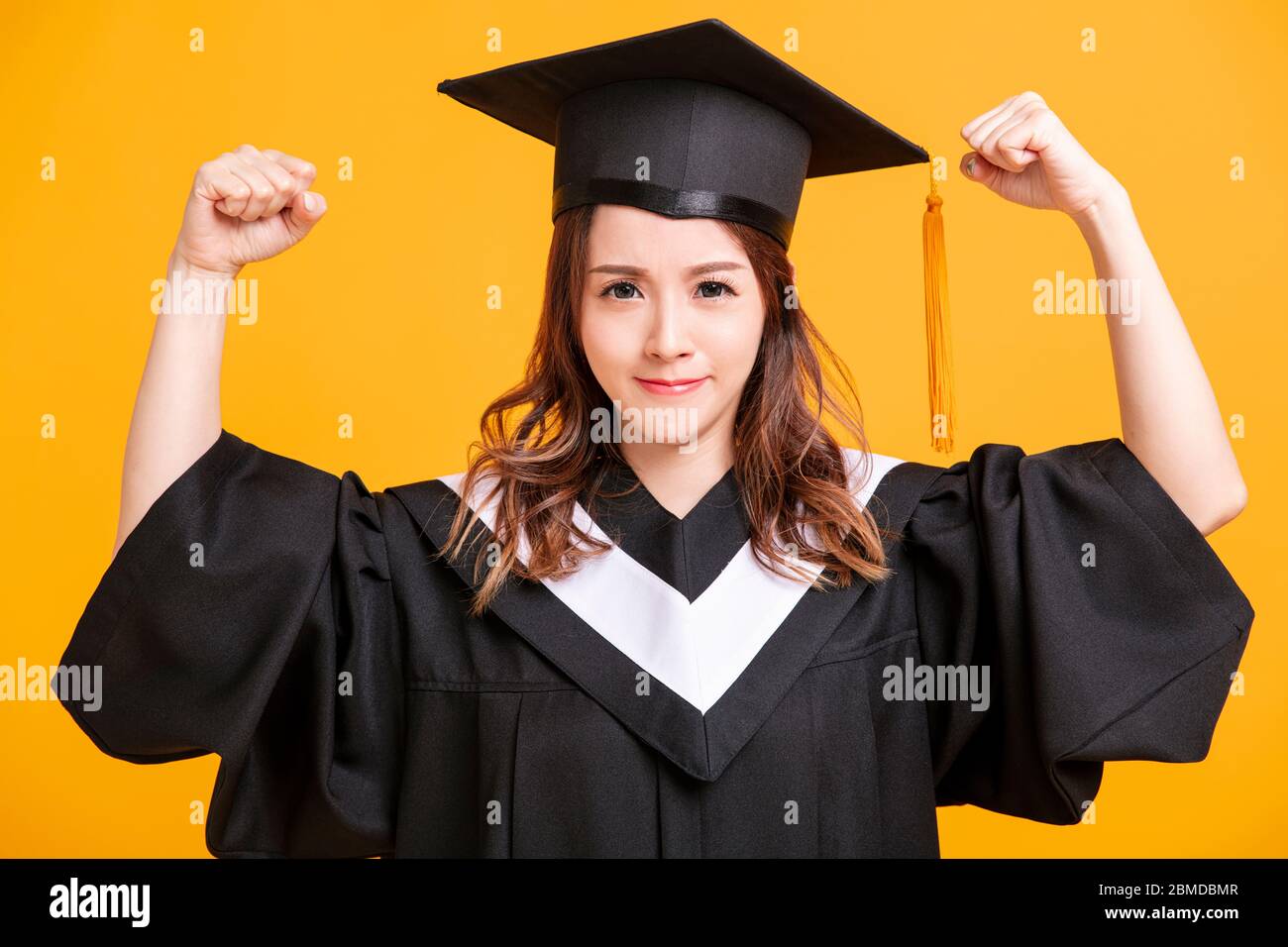 young woman in graduation gowns and showing success gesture Stock Photo ...