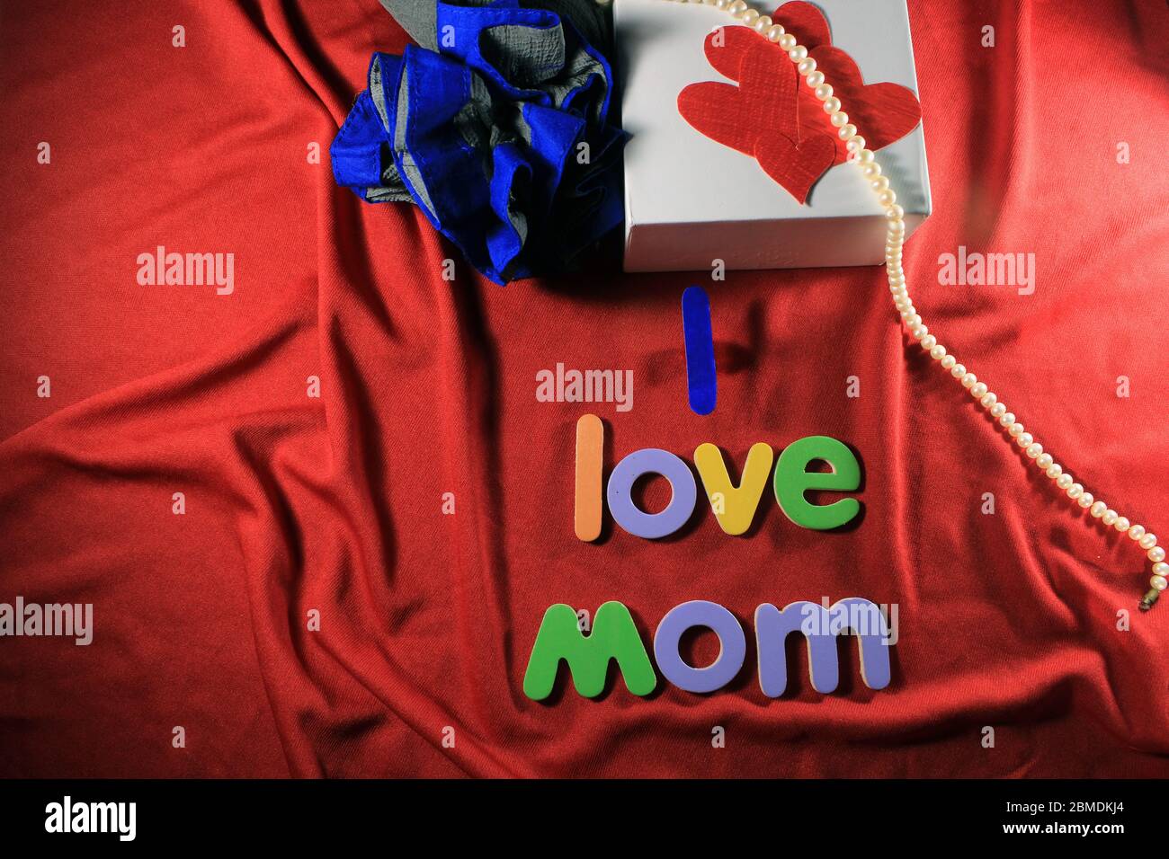 Colorful letters with I love mom isolated on red cloth background. I ...